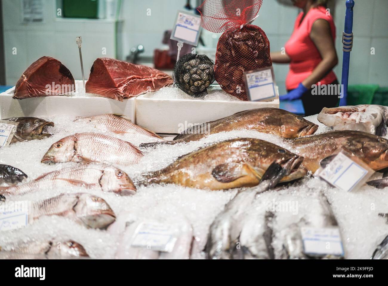 Fishmonger woman working inside seafood market - Focus on tuna fish ...