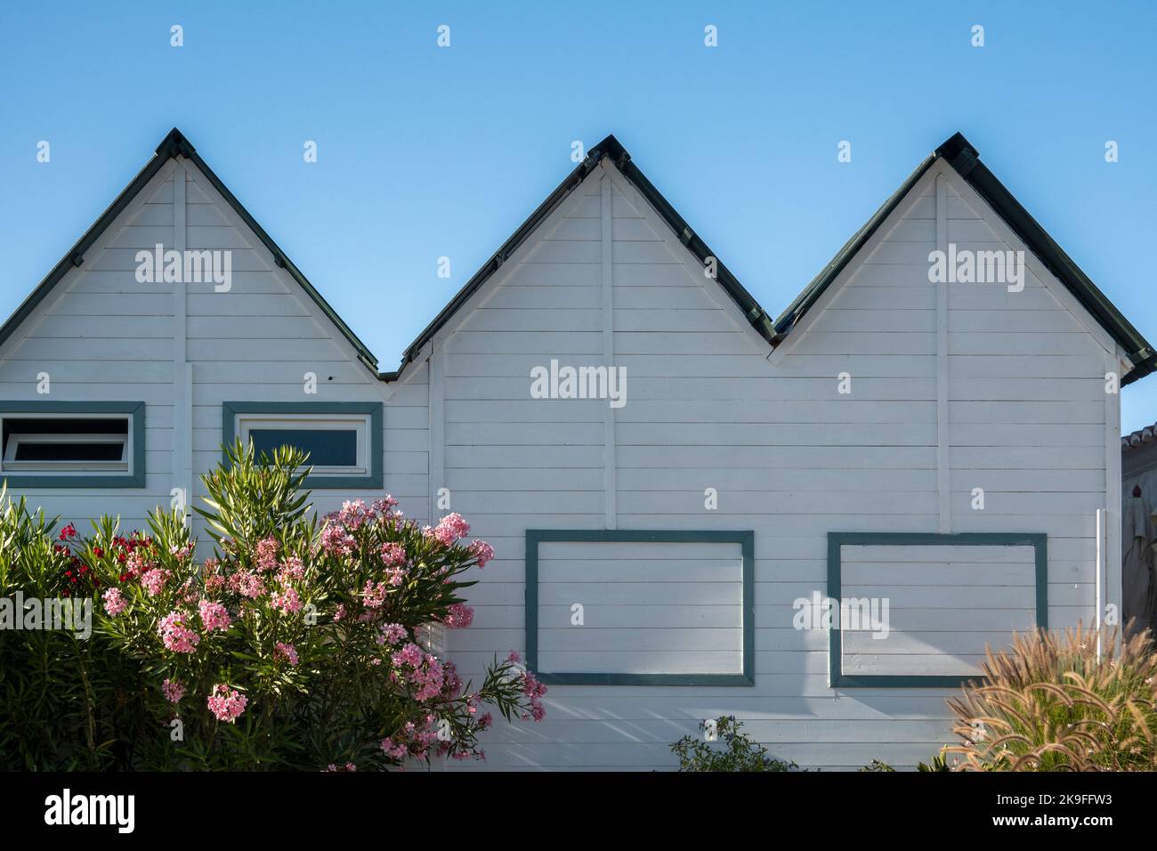 Row of white painted wooden beach houses with pointy rooftops located ...