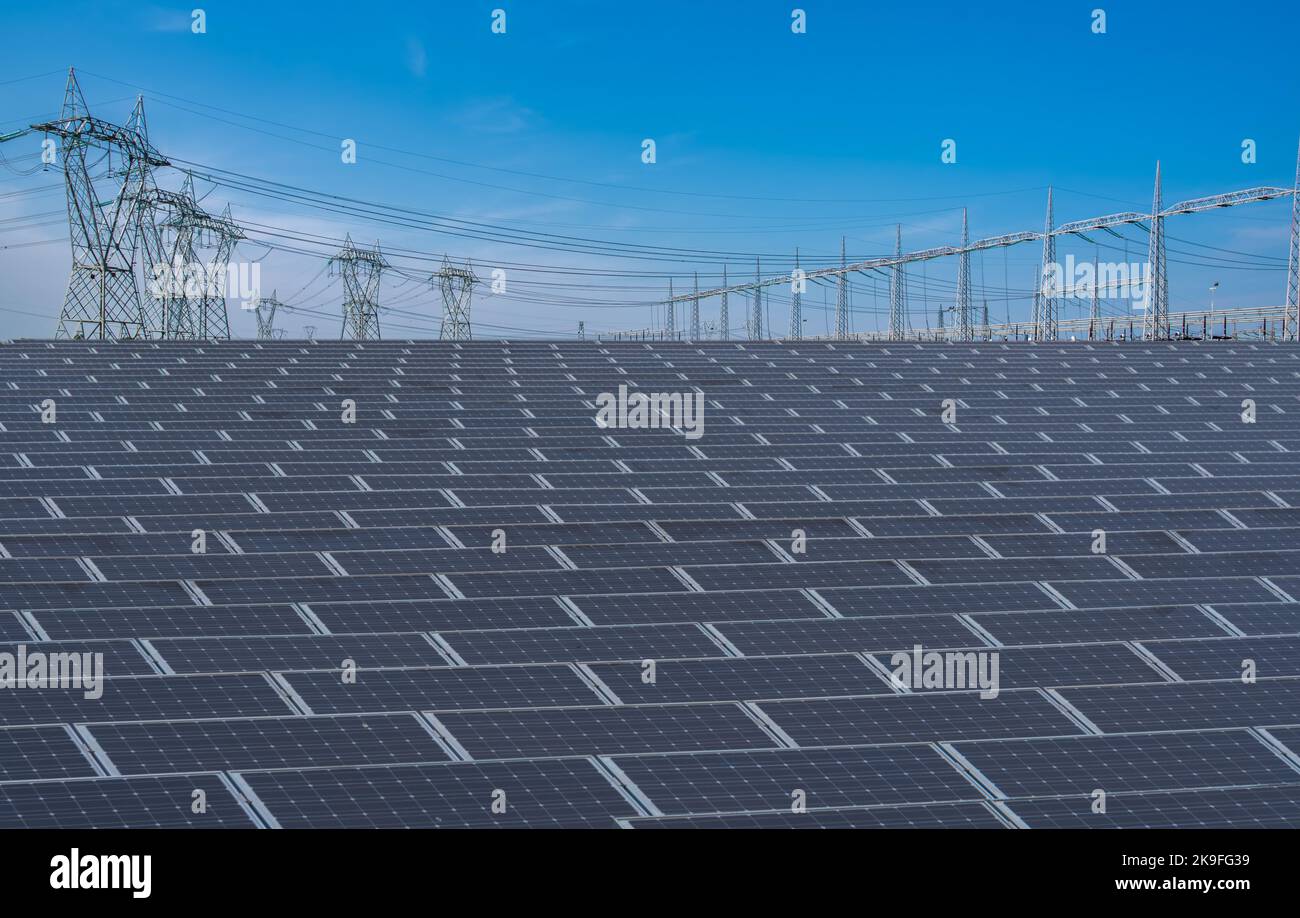 Solar panels with high voltage pylons on blue sky, electricity ...
