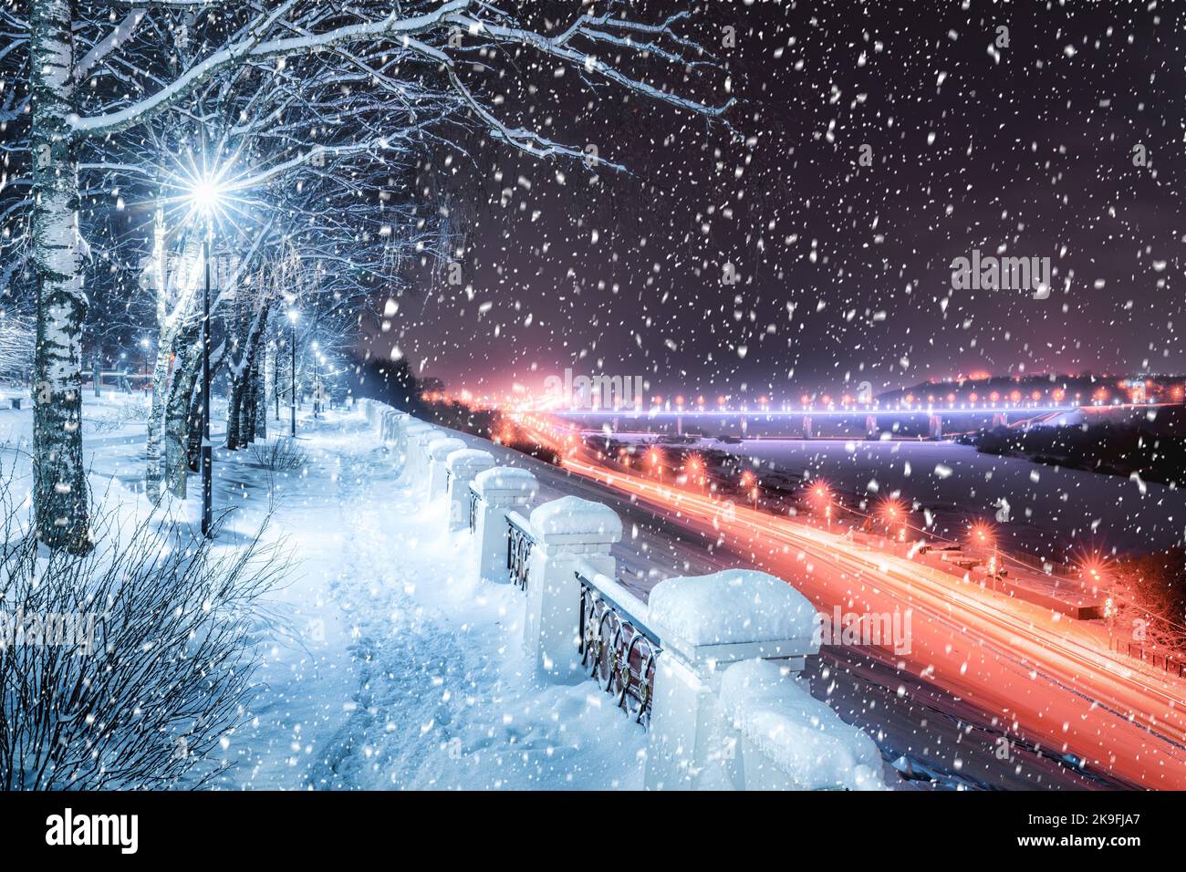 View of the night winter city covered with snow and the road with ...