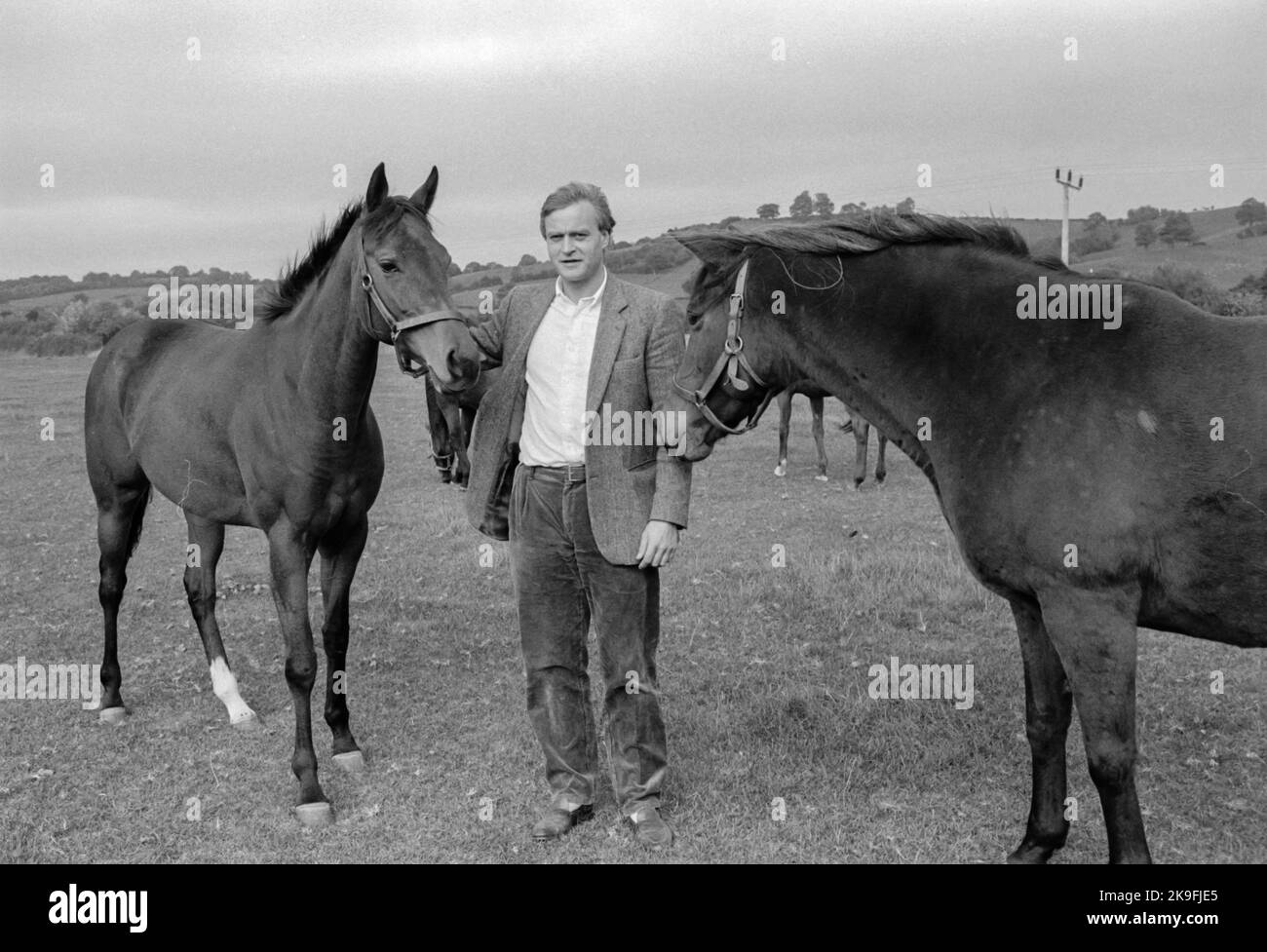 Monochrome photo of Author Peter Burden and horses on a grass field ...