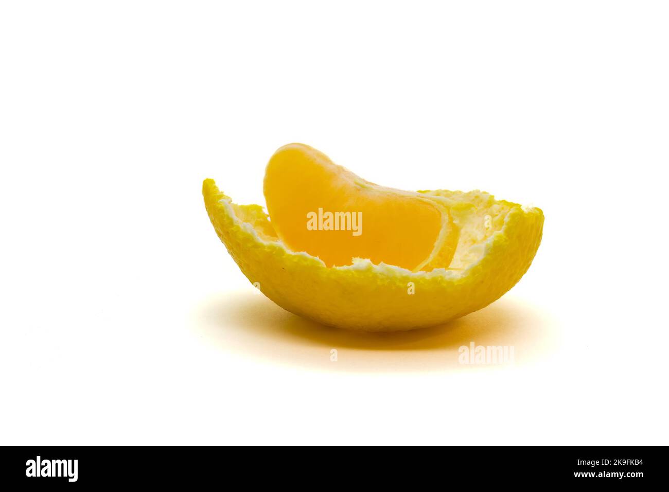 Single yellow slice of satsuma orange (Citrus unshiu) on a part of peel ...