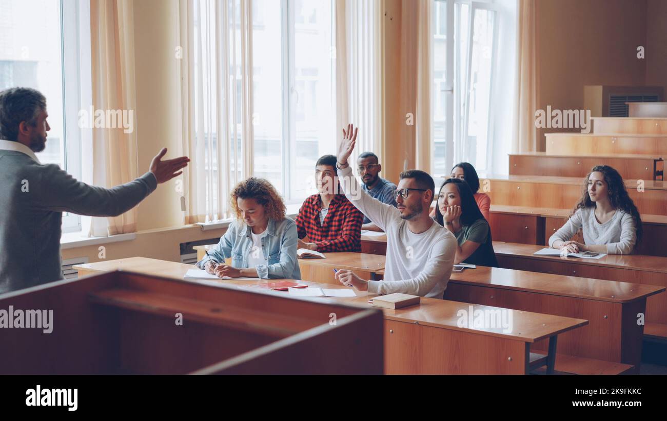 Smart guy successful student is raising hand and talking to professor ...