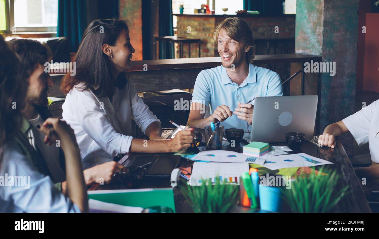 Cheerful guy is telling funny story to his coworkers and laughing ...