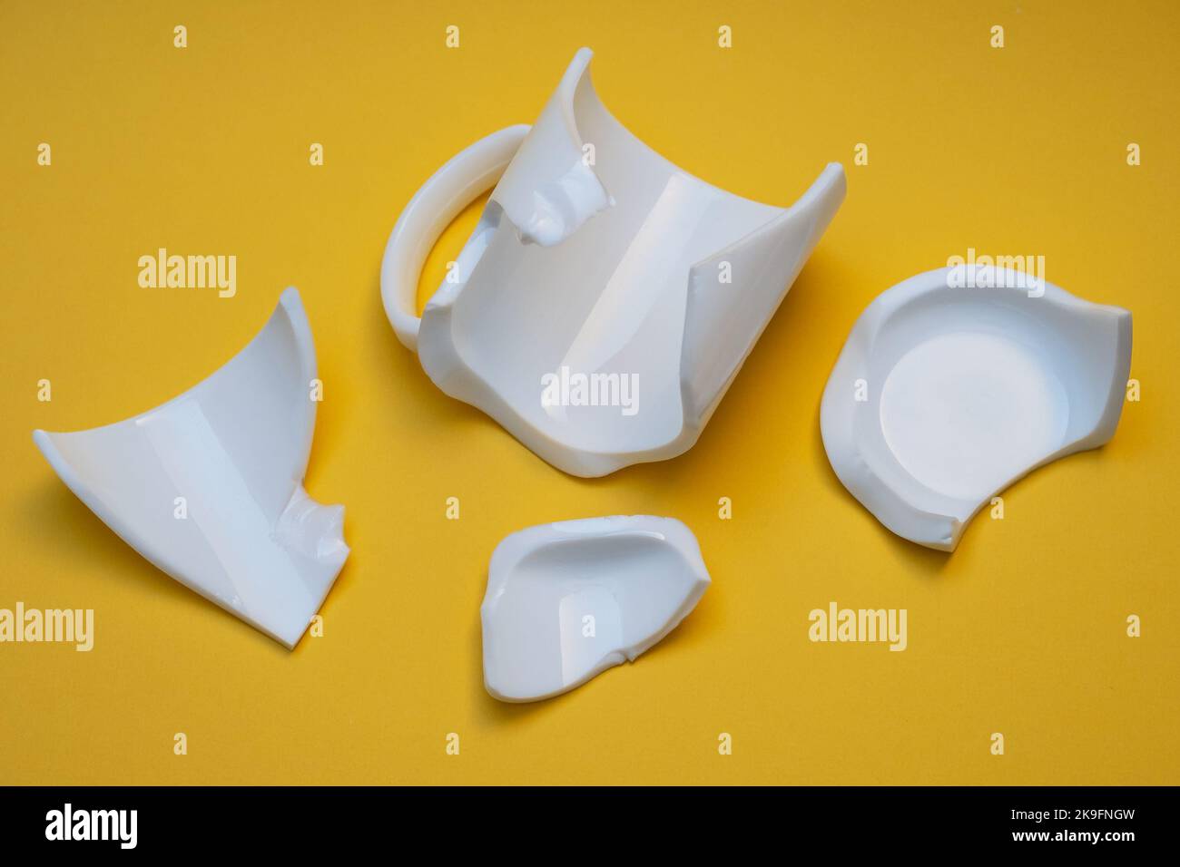 Splinters of the broken tea mug on a yellow background Stock Photo - Alamy