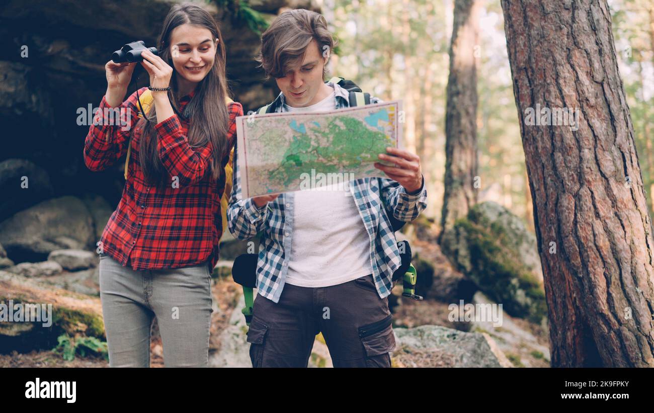 Handsome young man is looking at map while his female friend is ...
