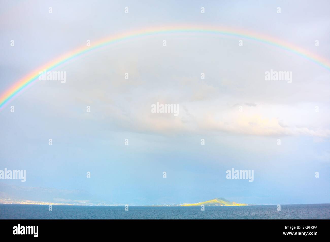 Rainbow over the island . Colorful natural phenomenon . Rainbow and sea ...