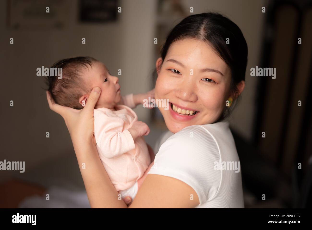 lifestyle shot on young and happy Asian Chinese woman holding tenderly her adorable newborn baby ...