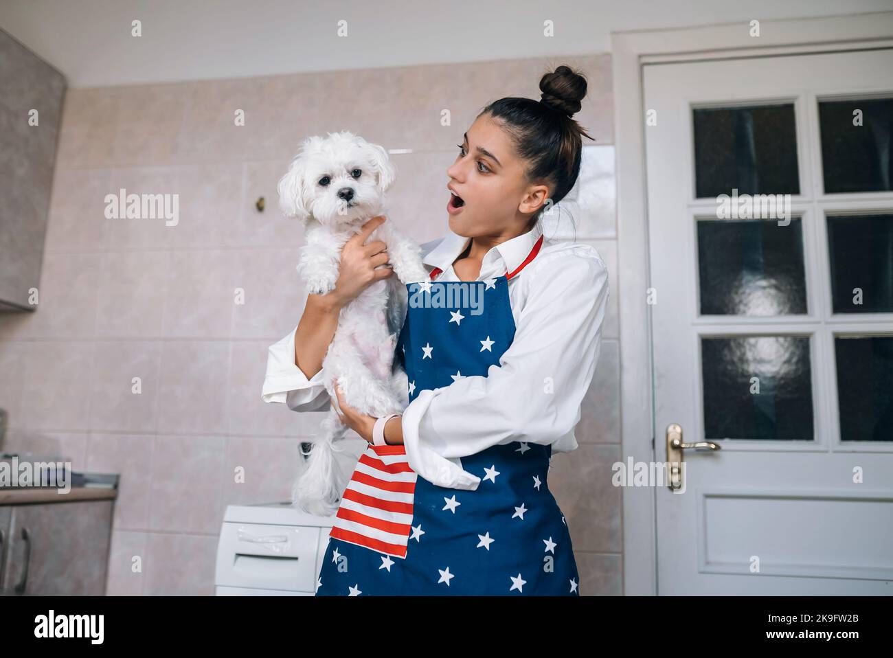 Smiling woman in kitchen holding cute white Maltese dog Stock Photo - Alamy