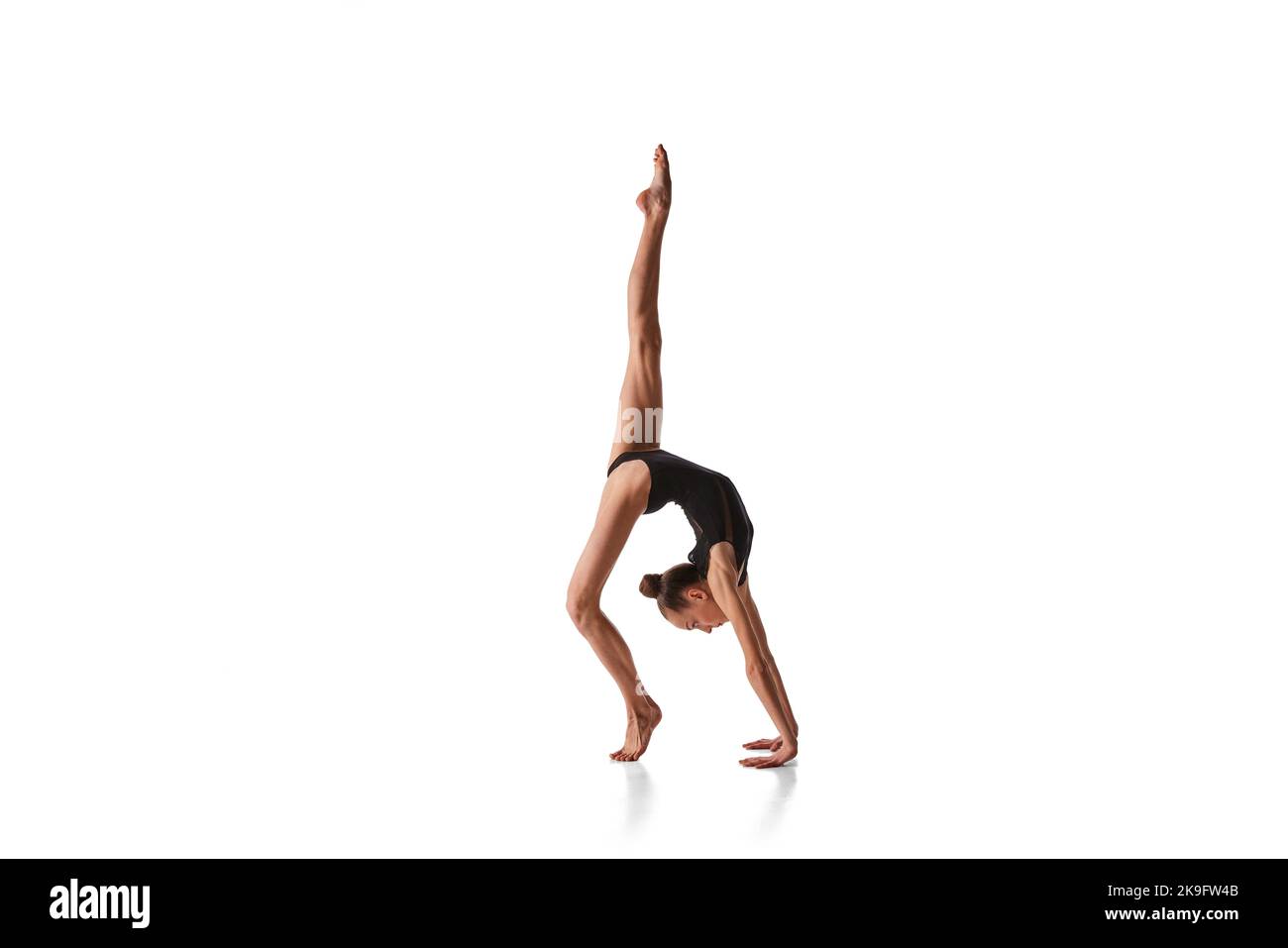 Balance. Portrait of junior gymnast in black sport swimsuit doing ...
