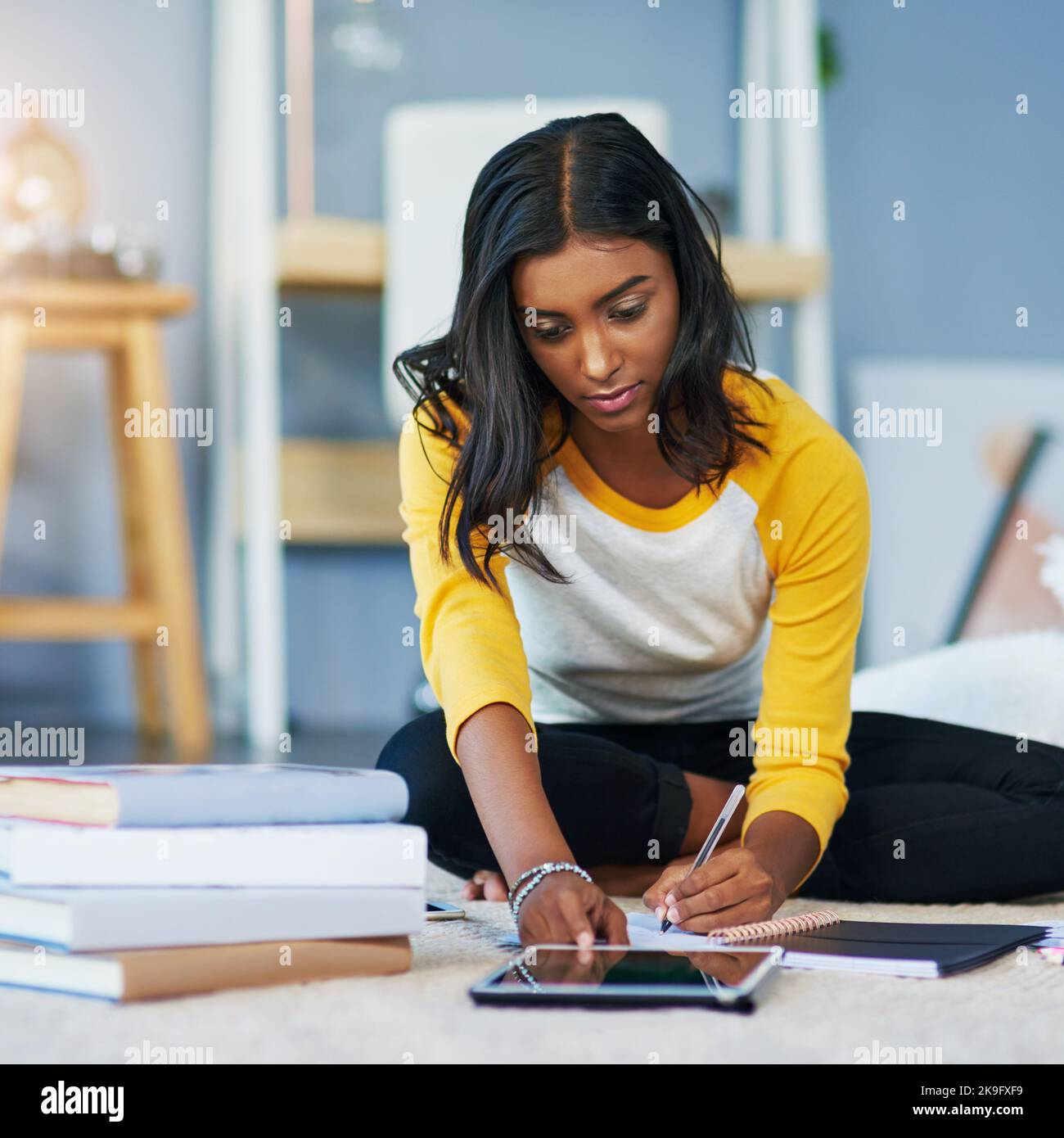 Making notes while studying helps. a young female student studying at ...
