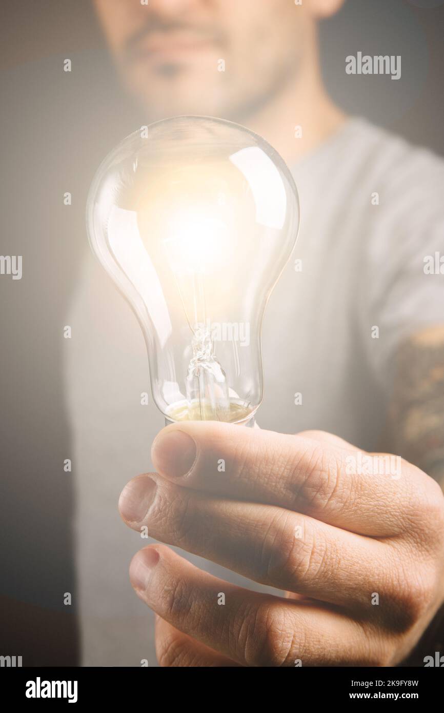 Man's hand holding lighted light bulb Stock Photo - Alamy