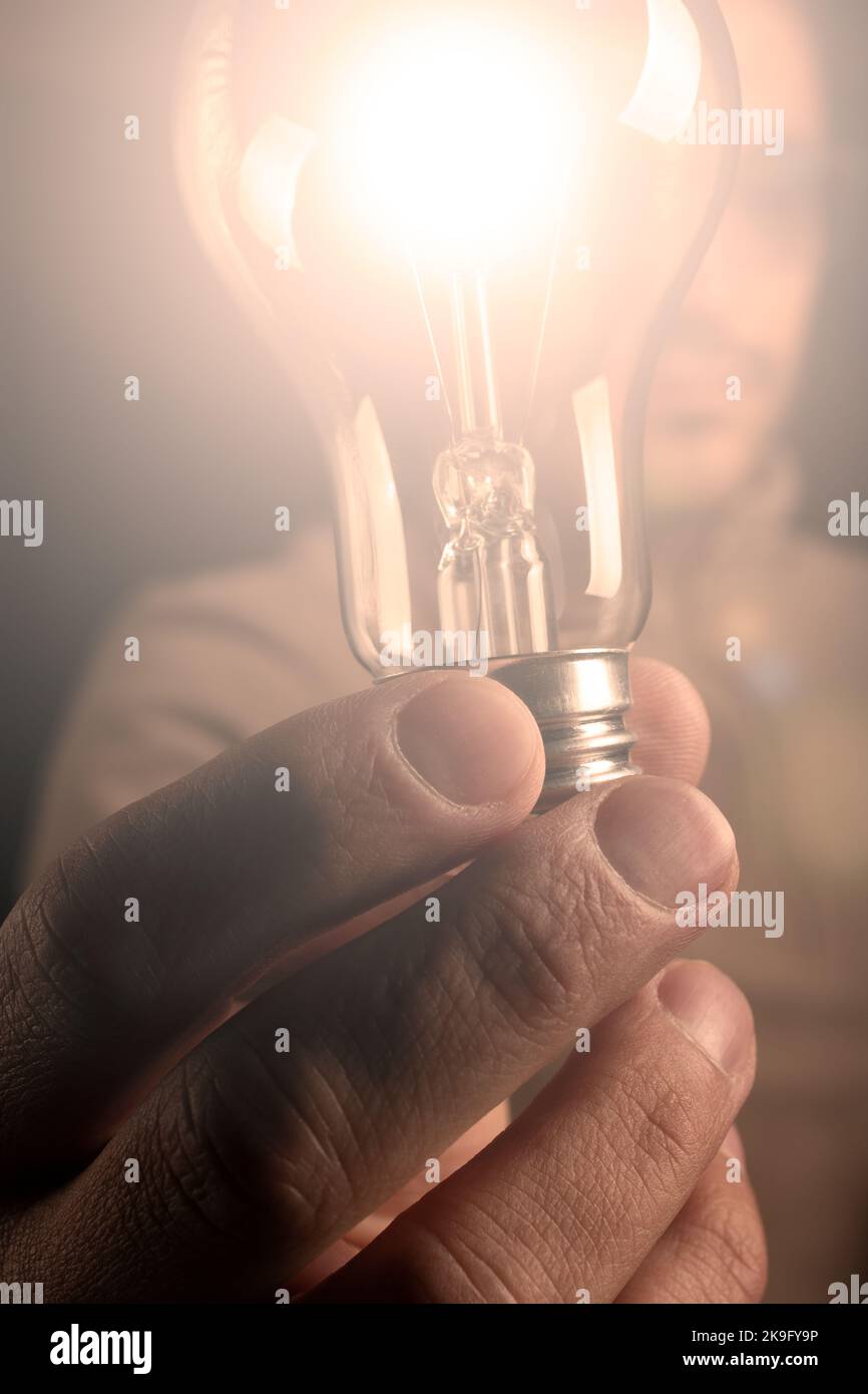 Man's hand holding lighted light bulb Stock Photo - Alamy