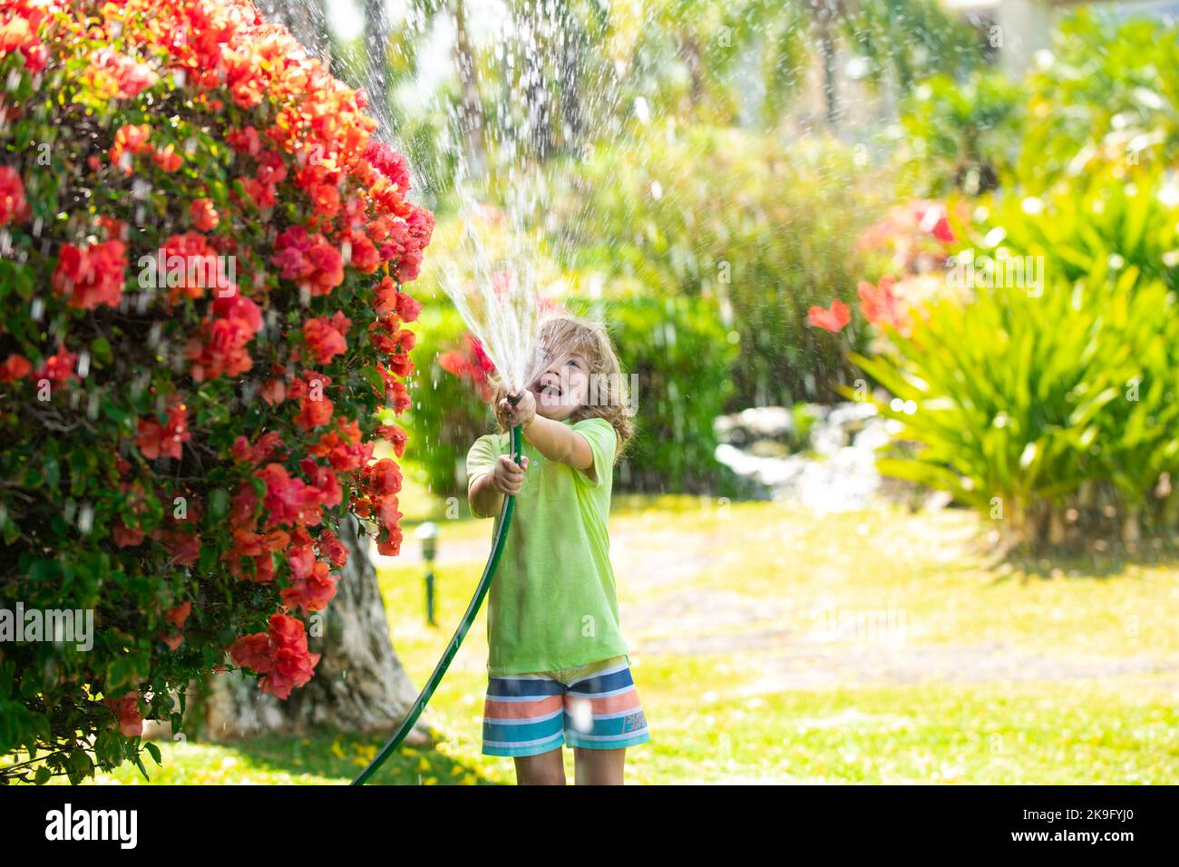 Child playing with garden hose in backyard. Funny excited kid having ...
