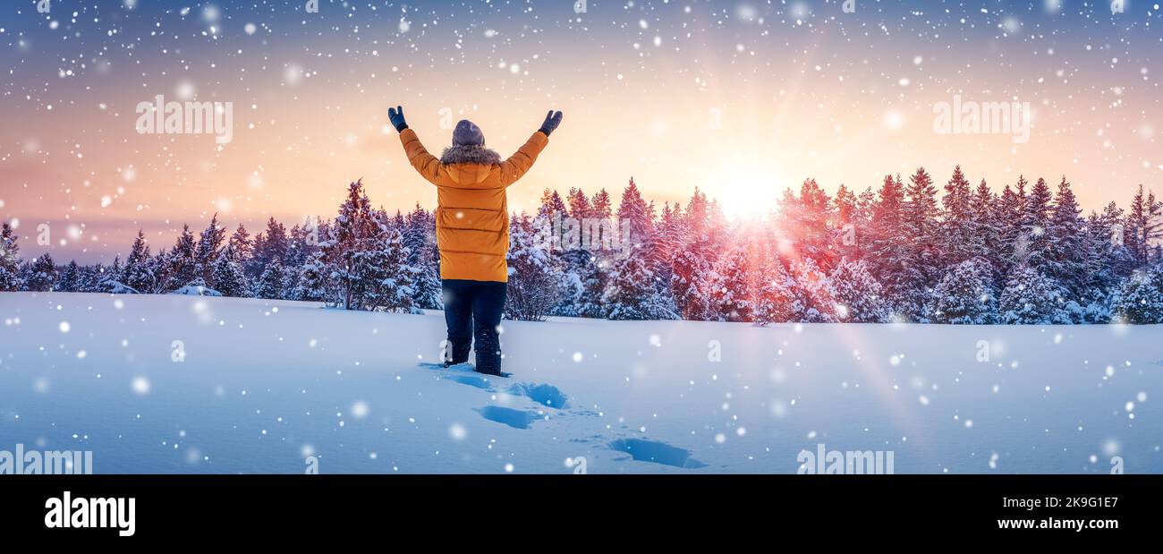 A woman stands on a snowy field with her hands raised up Stock Photo ...