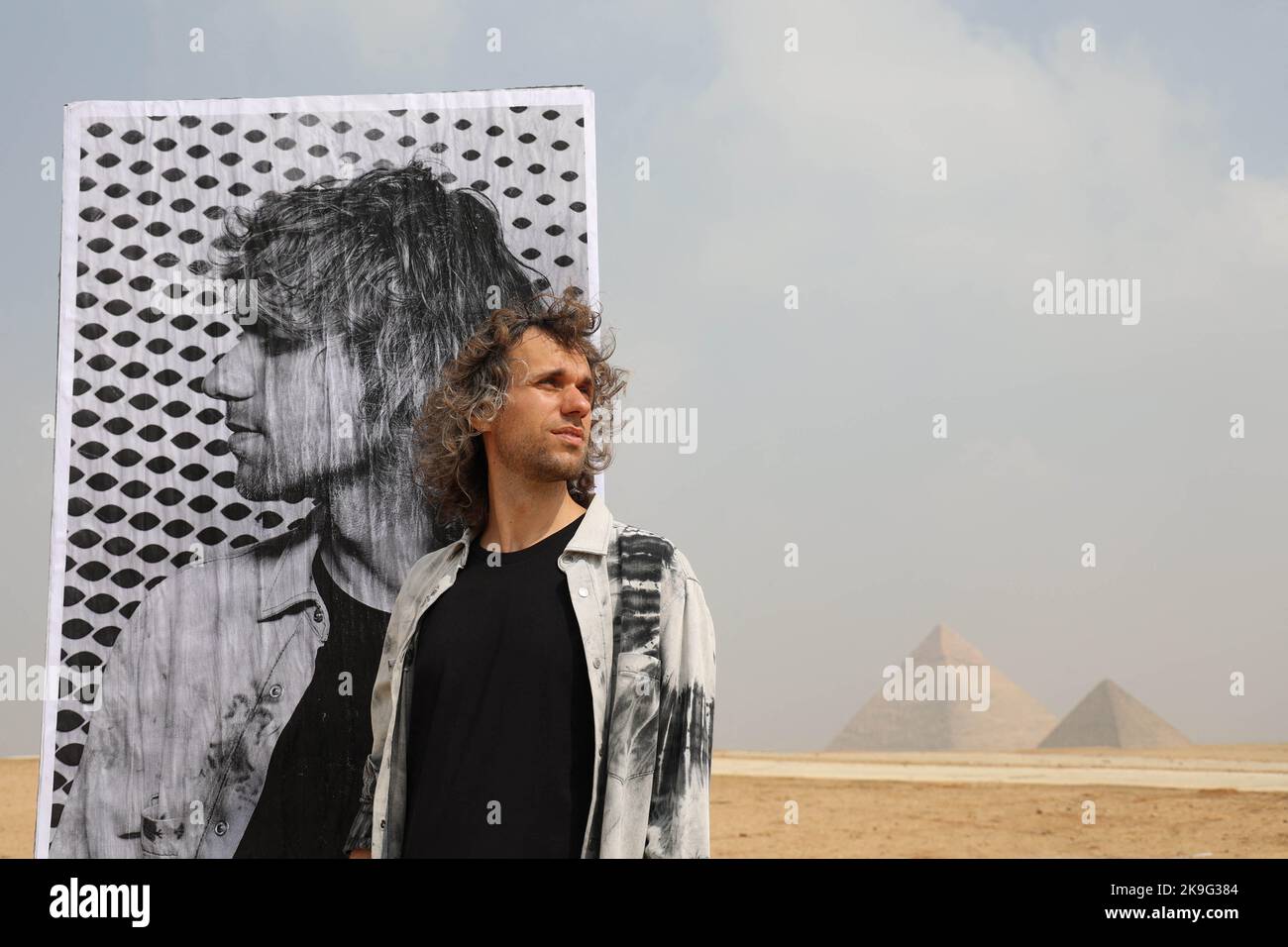 Italian artist Emilio Ferro poses next to his portrait by French artist ...