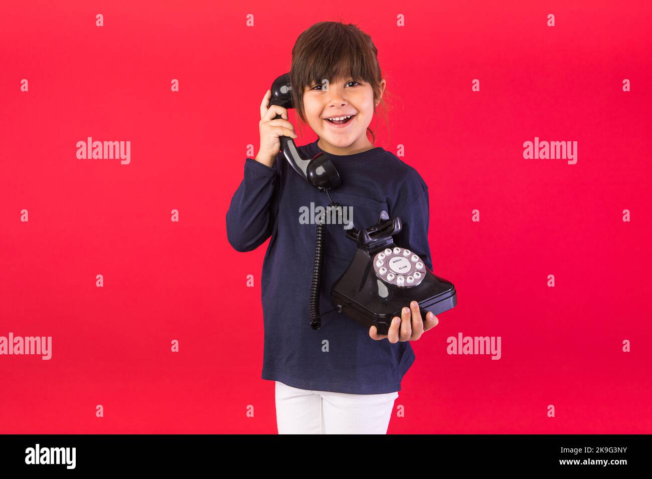 Smiling brunette-haired girl, wearing blue sweatshirt and white pants ...
