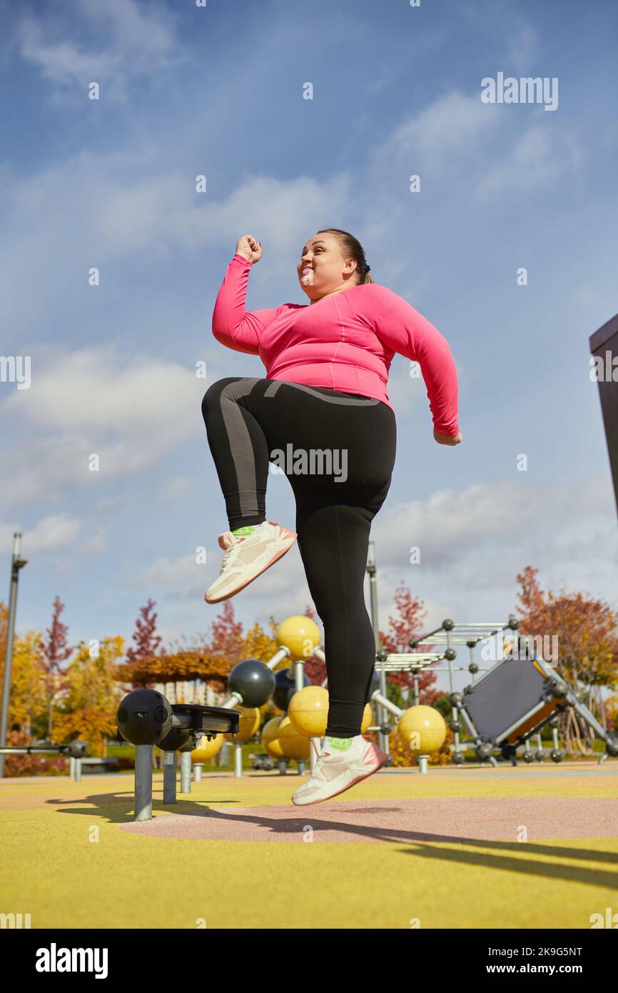 Young plump woman in activewear workout at street public sportsground ...