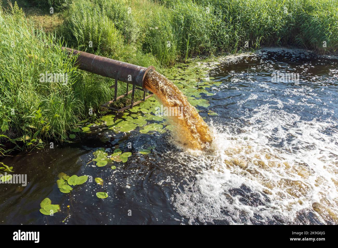 pollution from the pipe enters the river. Dirty water flows into the ...