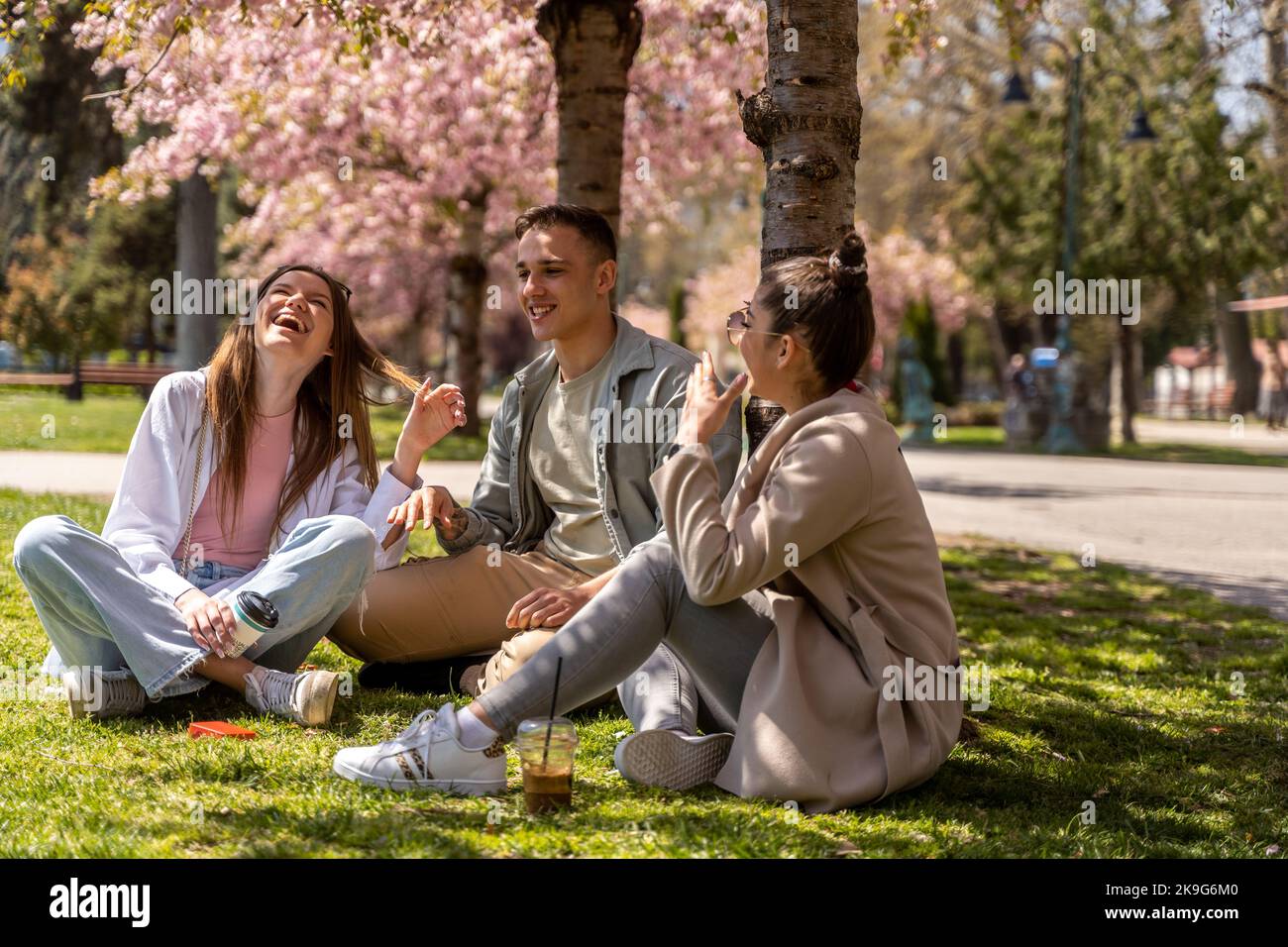 Group of cheerful friends sitting outdoors and drinking coffee on ...