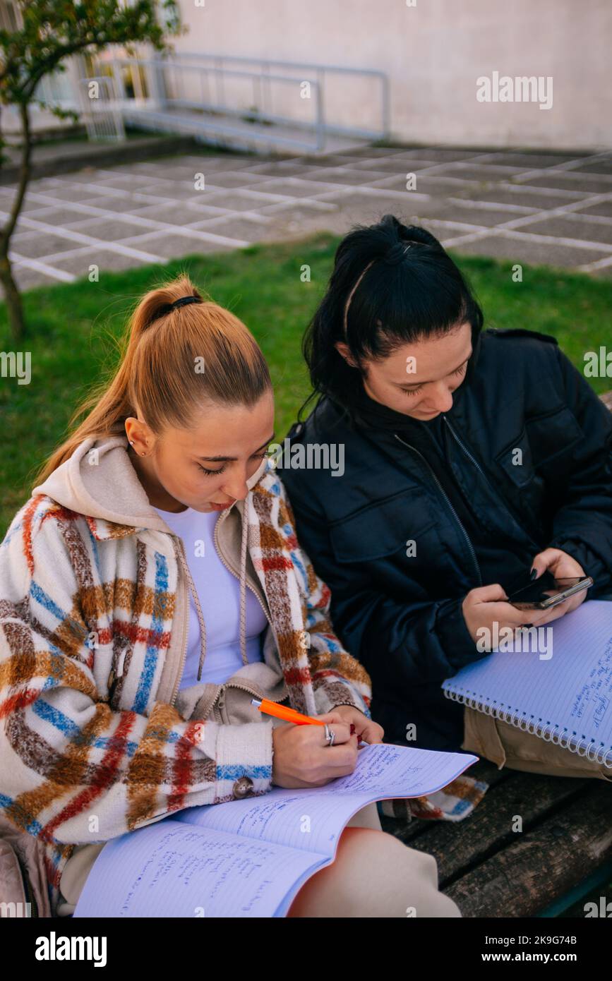 A brunette female student is reading notes from her phone while her ...