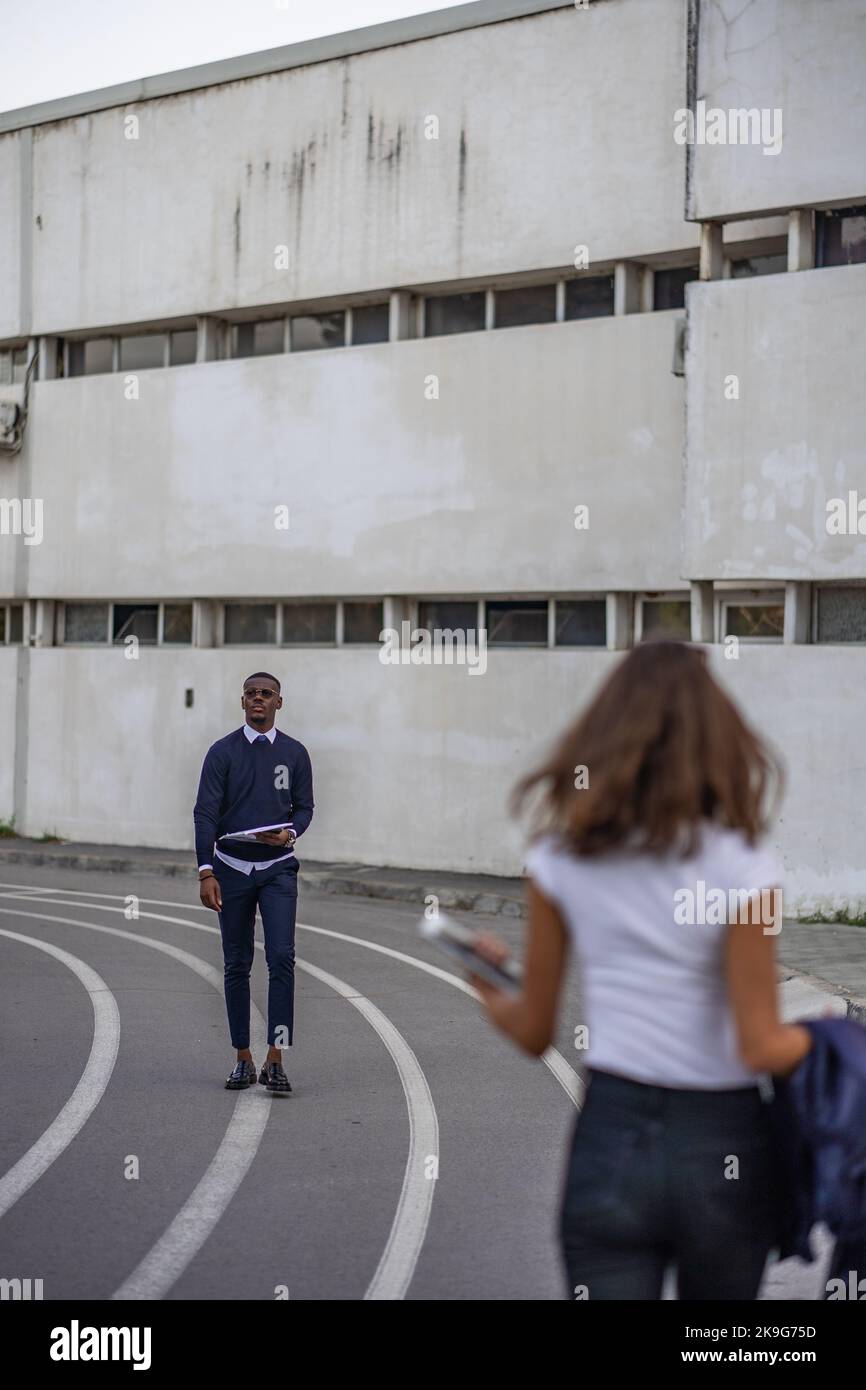 Two multiracial business partners are walking towards each other while ...