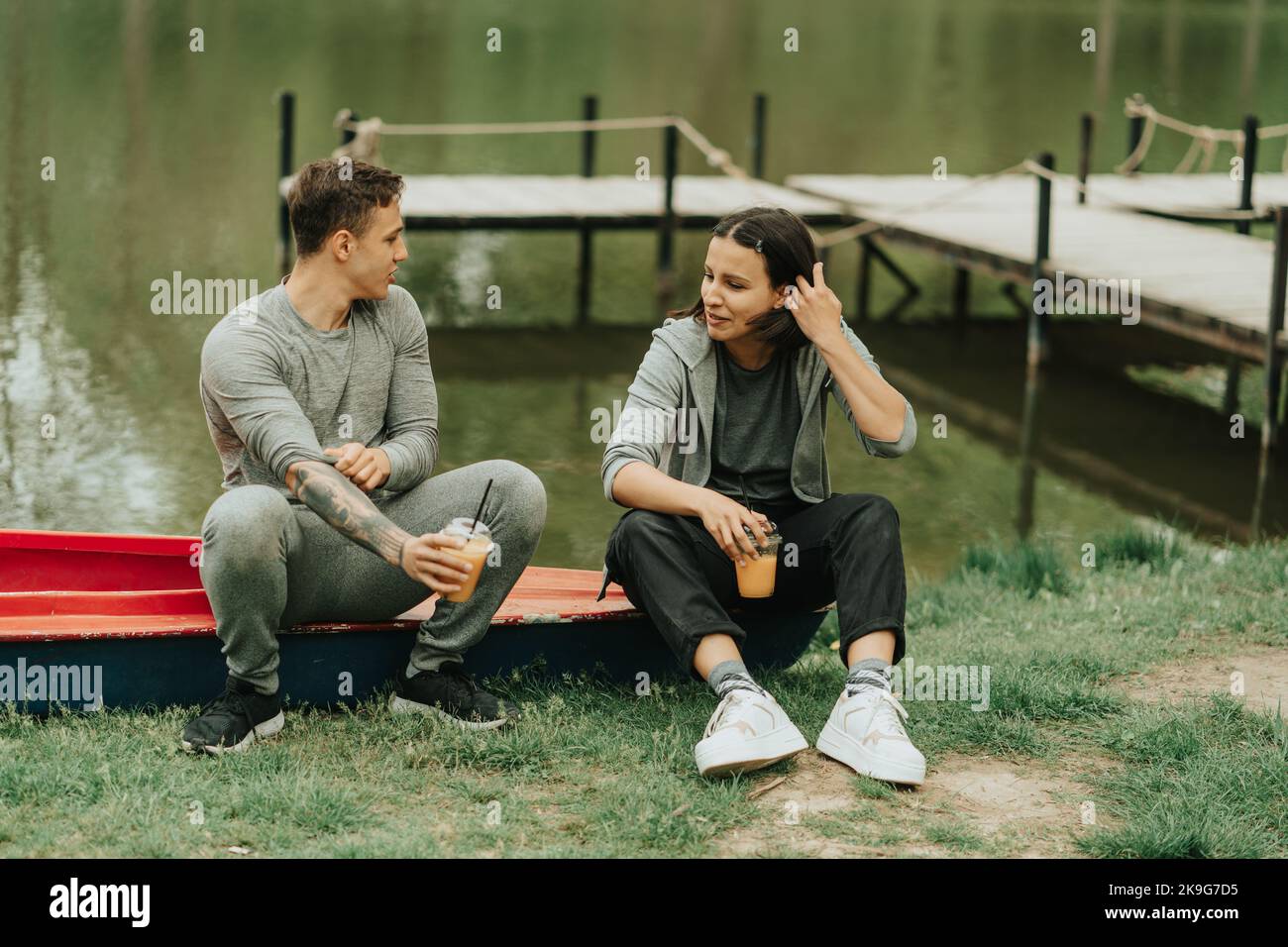 Beautiful couple talking while sitting on a red kayak in the park near ...