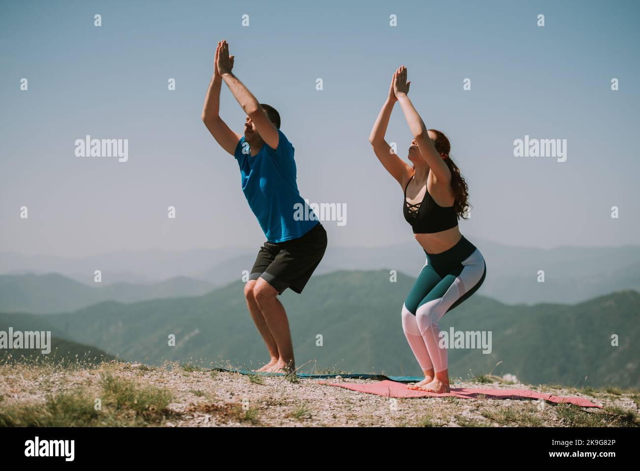 Yoga partners making some yoga poses on yoga mats at the top of the ...