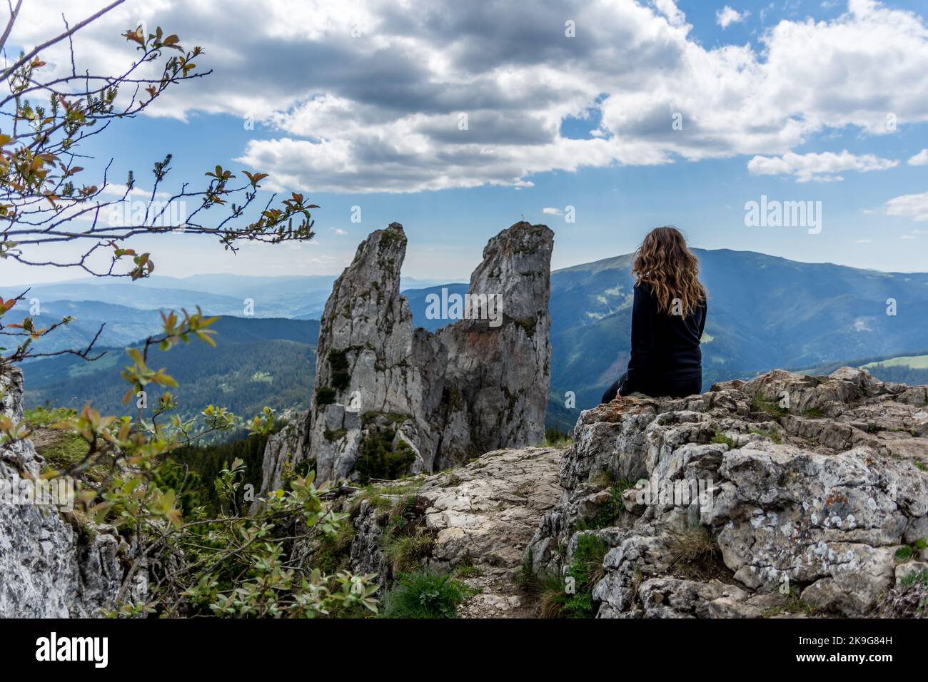 A woman sitting on a cliff looking at the mountain view Stock Photo - Alamy