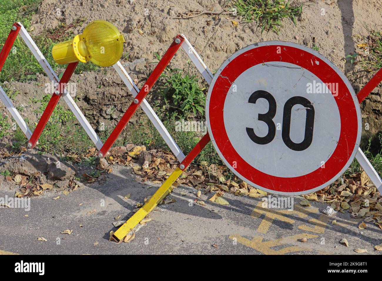 Speed limit traffic sign and a yellow light at the road construction ...