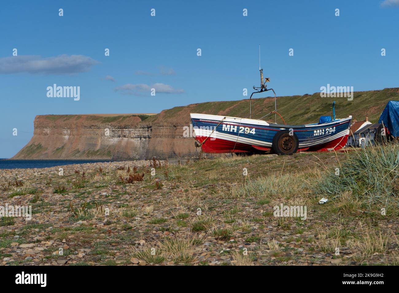 A red blue fishing boat at the base of Huncliff in Saltburn, UK Stock ...