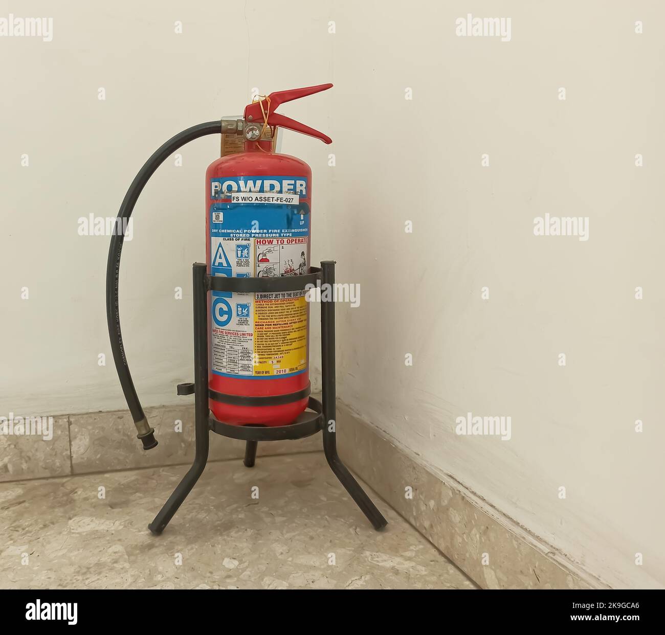 A closeup picture of a fire extinguisher placed in the corner in a Mall ...
