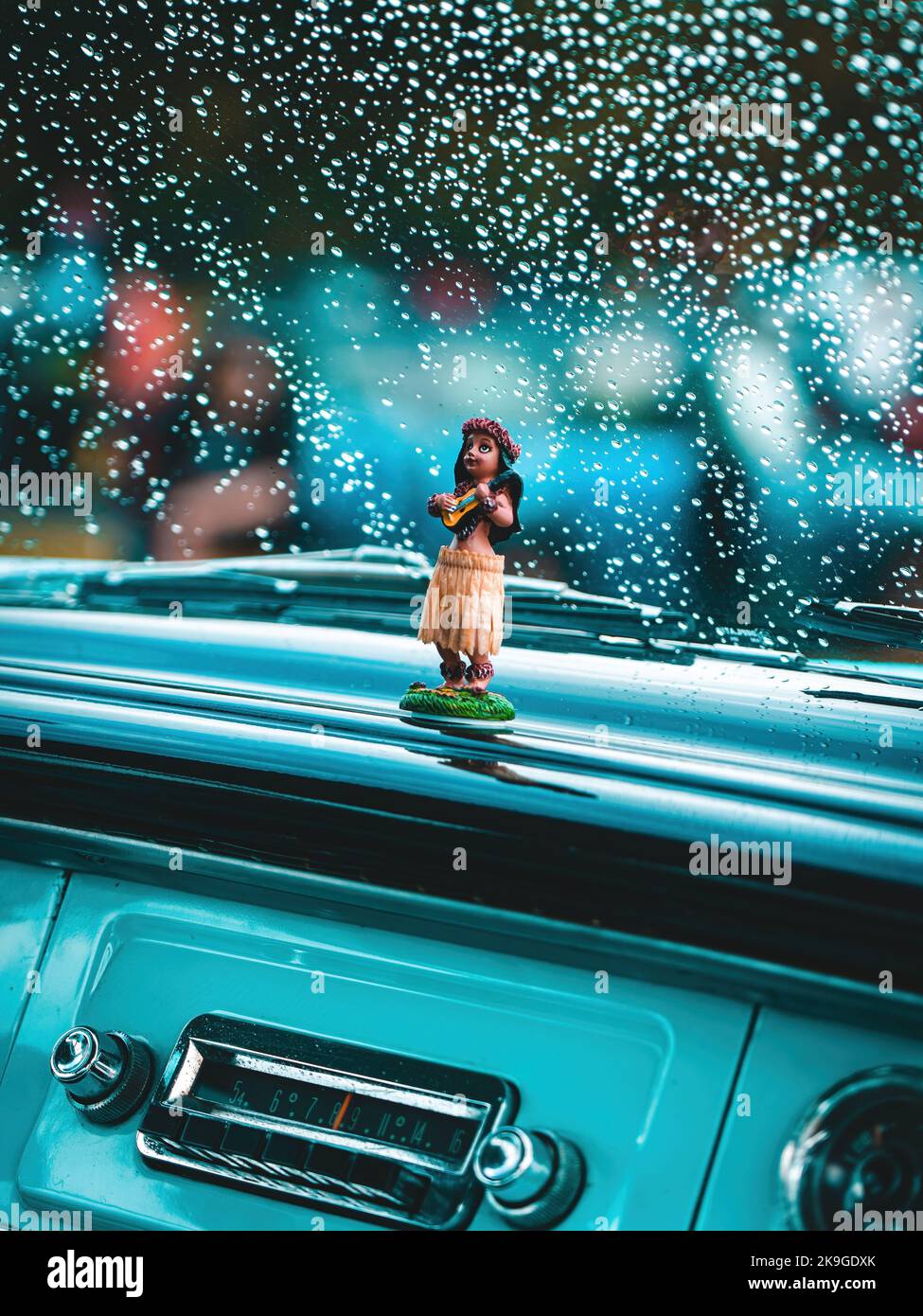 A vertical view of a Hula Girl figurine on the dashboard of a classic ...