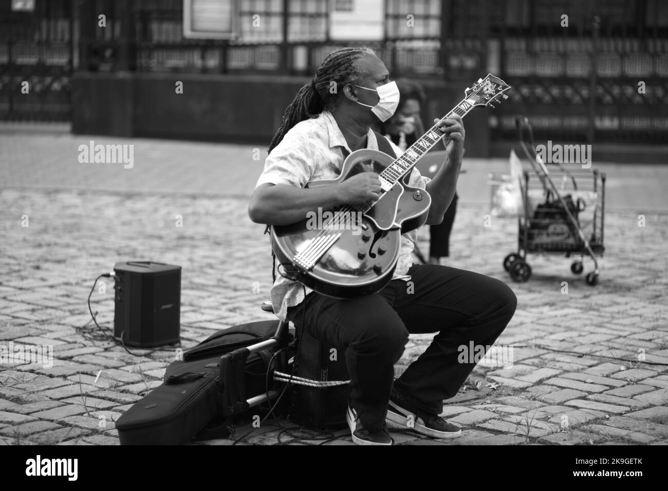 A black street musician in a mask playing Guitar in the village in New ...