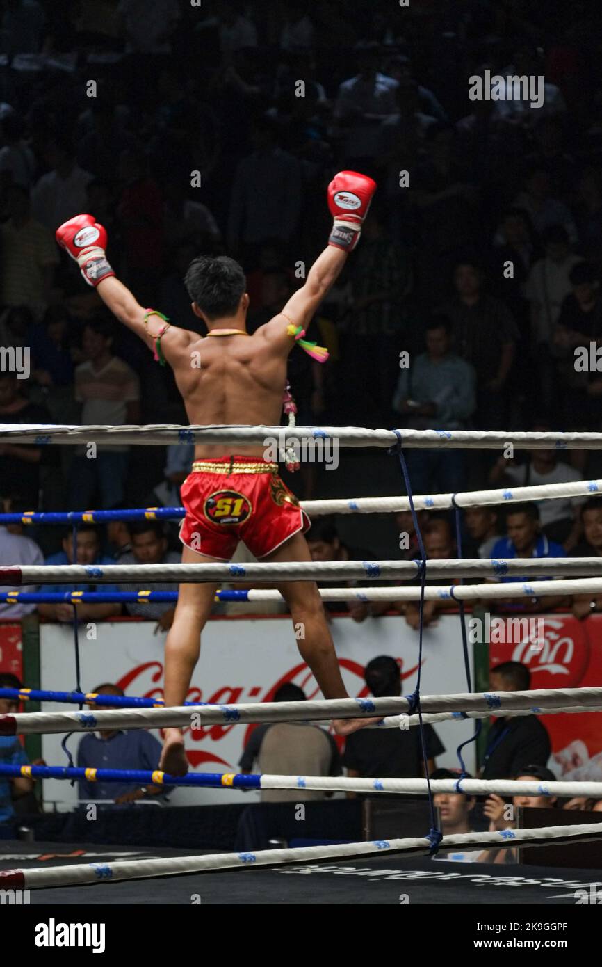 A Muay Thai boxing fighter celebrating a win by jumping on the ring ...