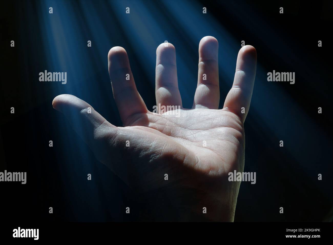 man hand up gesturing in the shadows, dark background Stock Photo - Alamy