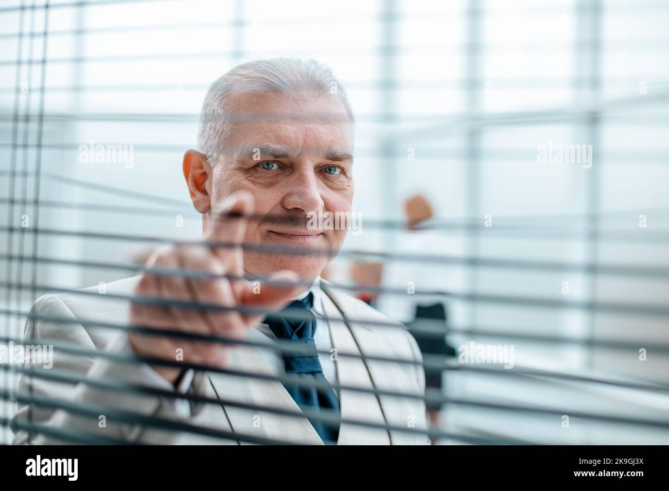 Mature businessman looking through office window blinds Stock Photo - Alamy