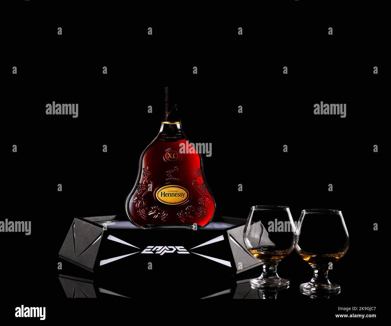 A Hennessy Cognac bottle and two cups placed in front of a black ...