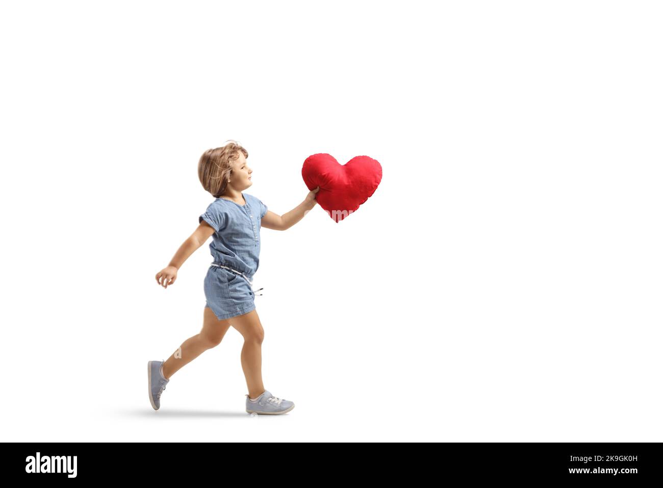 Full length profile shot of a little girl running and carrying a red ...