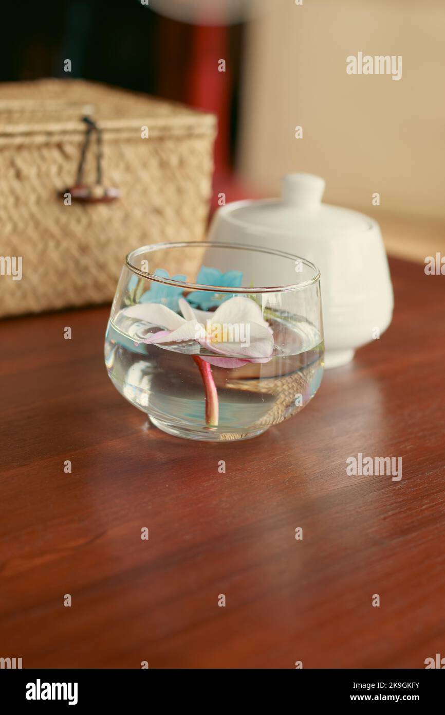 A frangipani flower in a glass of water as a table centerpiece showing ...