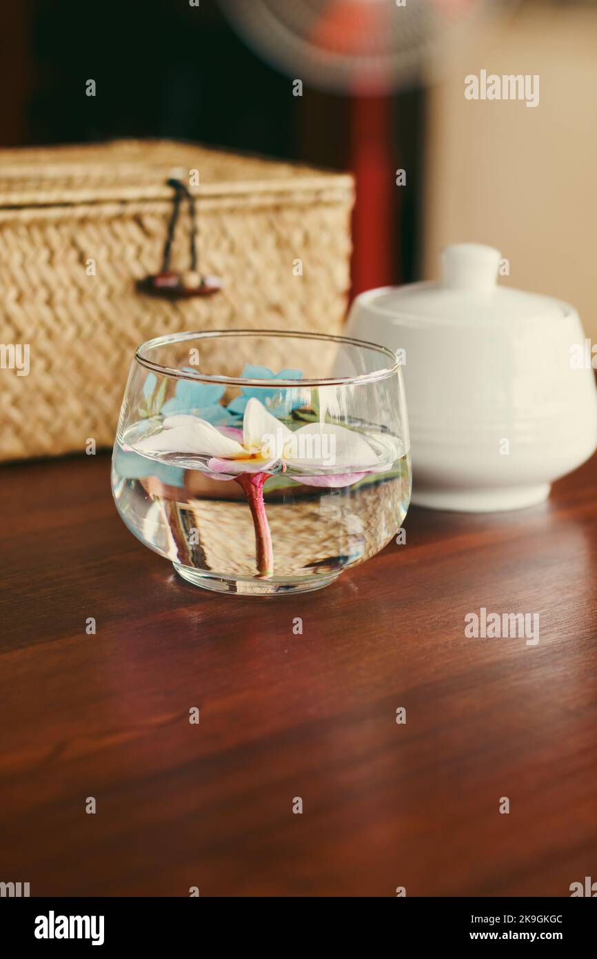 A frangipani flower in a glass of water as a table centerpiece showing ...