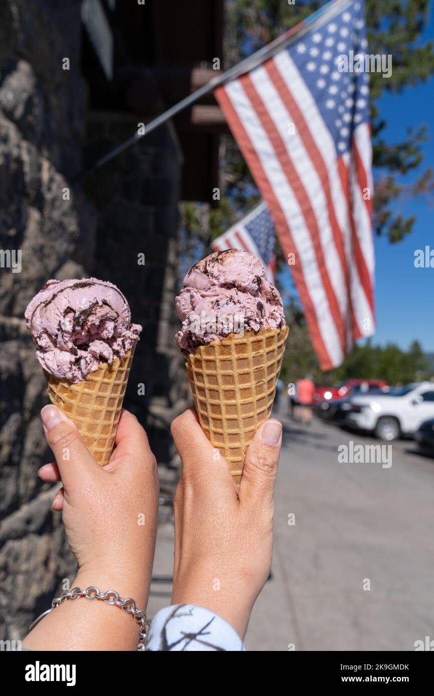 Two hands hold up ice cream waffle cones with American flags in the ...