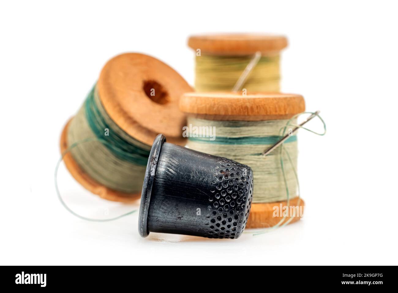 An old wooden spool of thread and a needle on a white background close ...