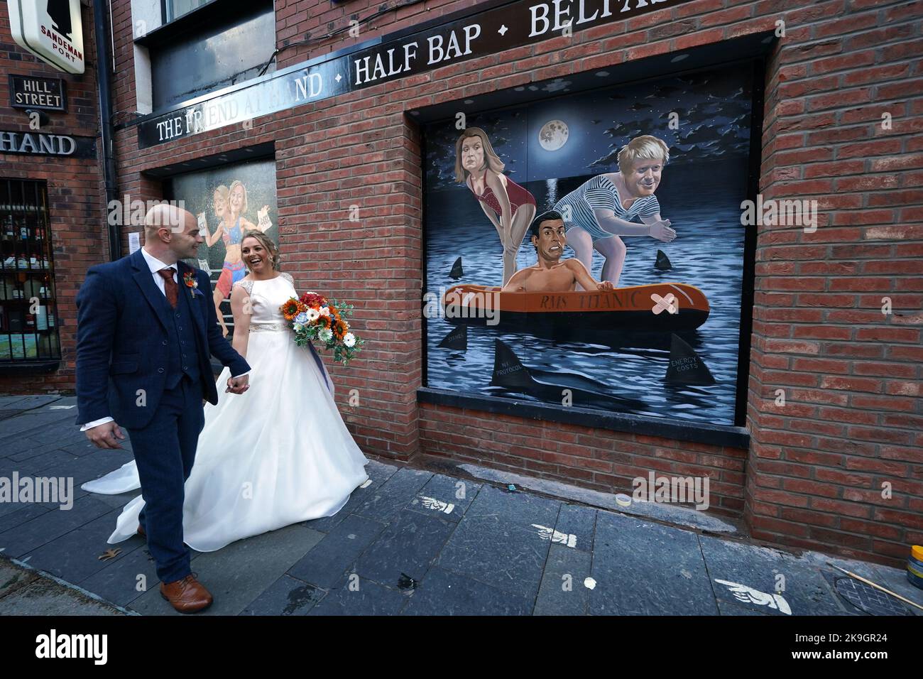 Newlyweds Gerard and Anne McDonnell walk past a mural by artist Ciaran ...