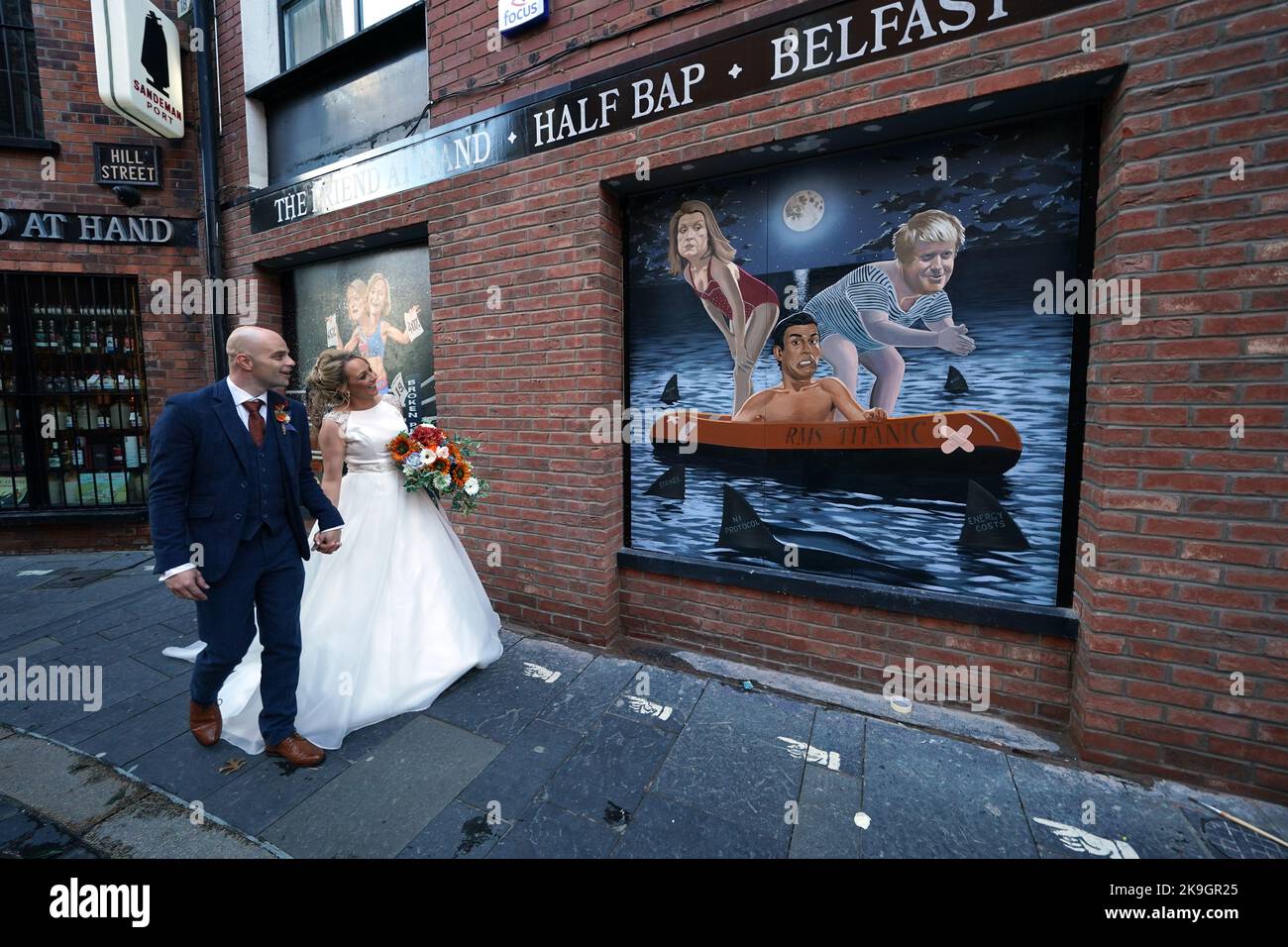 Newlyweds Gerard and Anne McDonnell walk past a mural by artist Ciaran ...