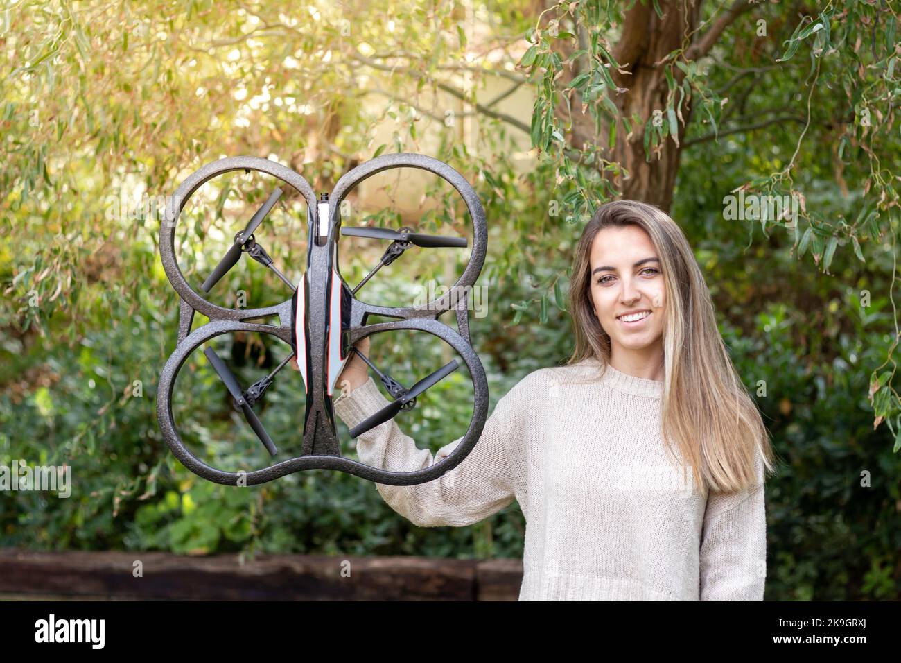 Beautiful young girl showing in her hands a large flying drone with ...