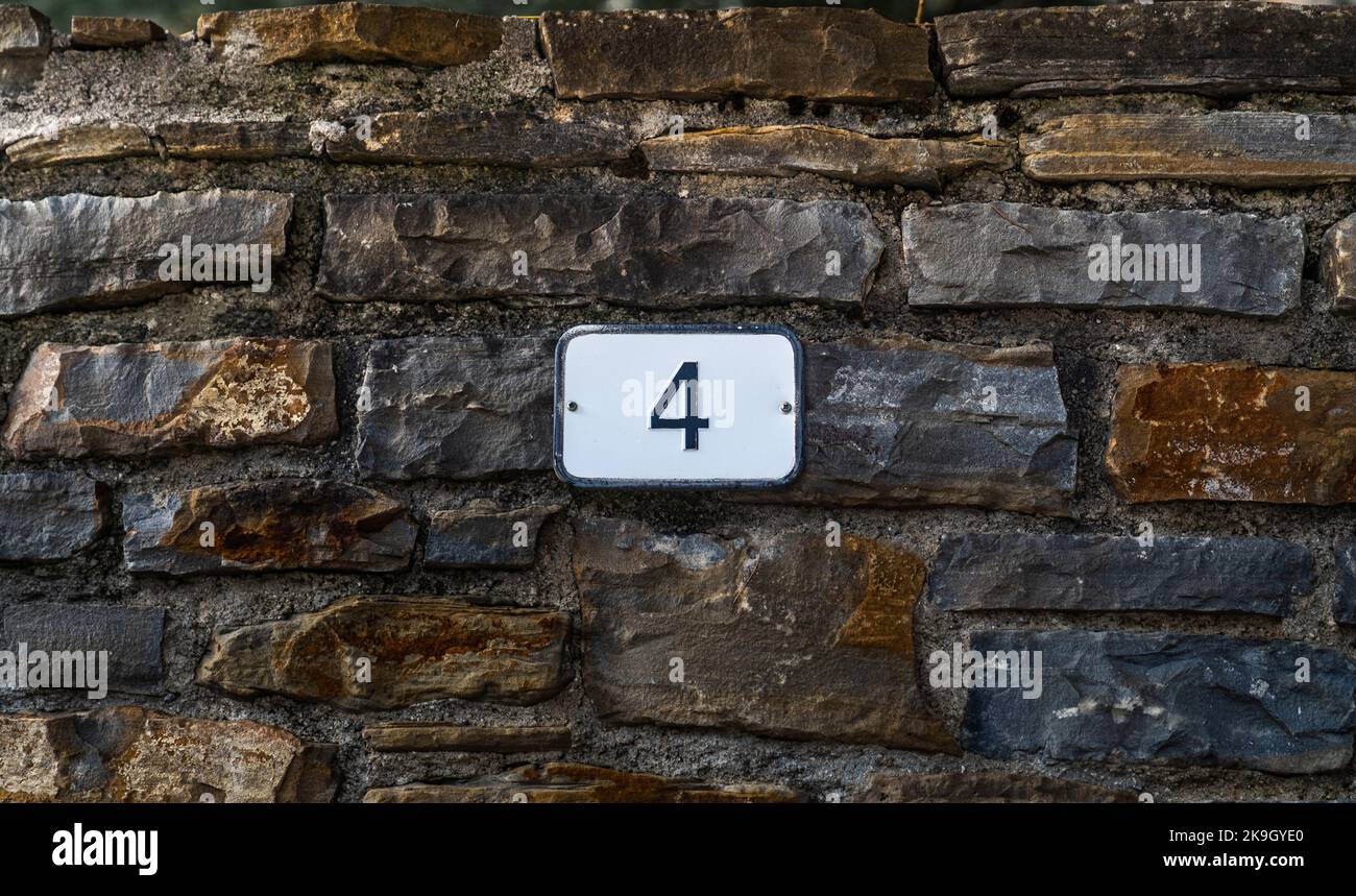 House number 4. Number 4 on a rock wall of a rural village street ...