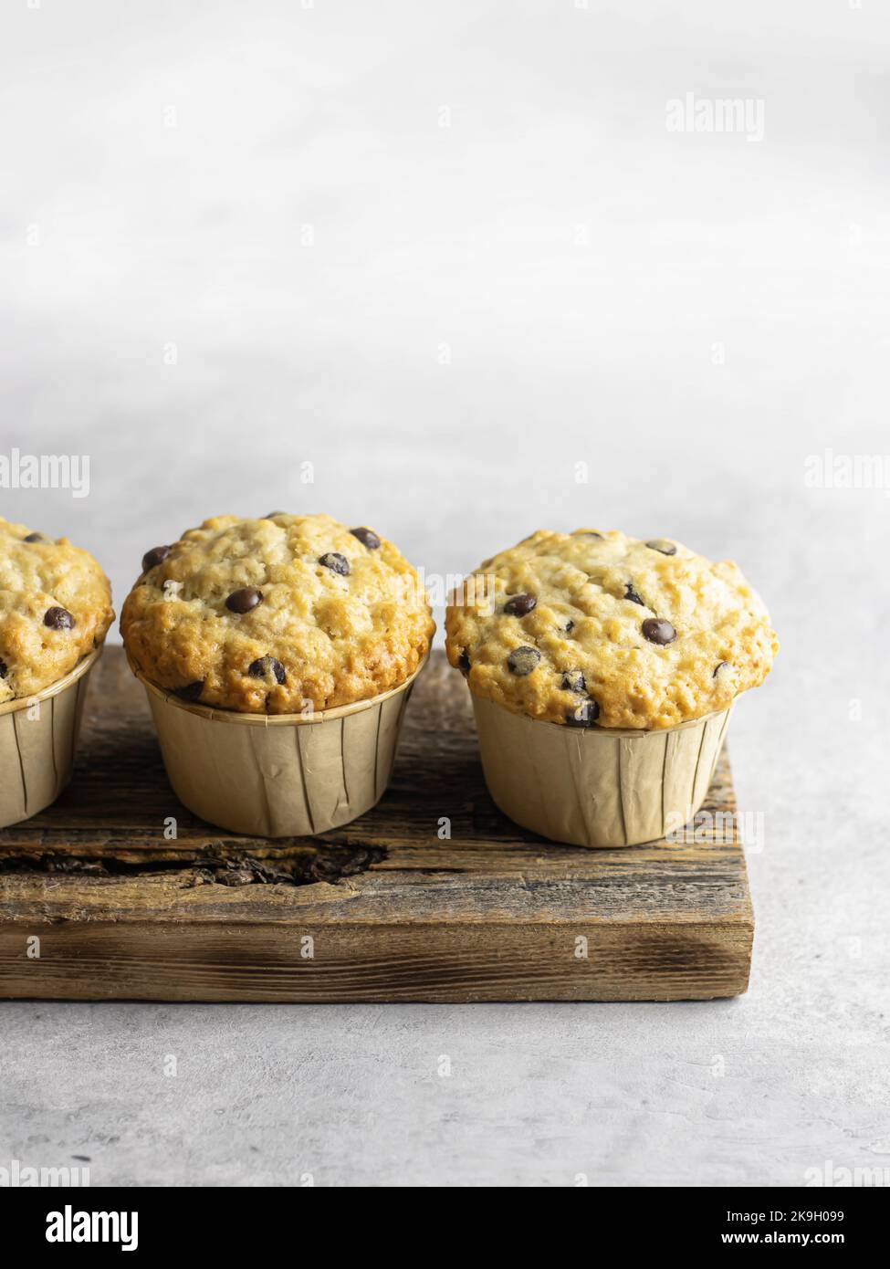 Chocolate chip muffins on wooden board on light gray background with ...