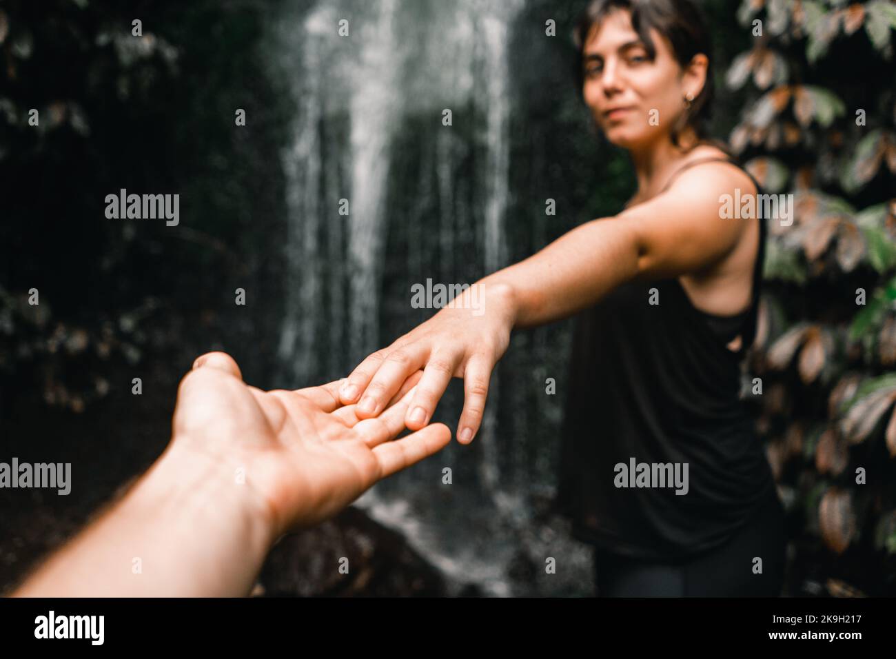 young caucasian girl with disheveled hair by waterfall reaching out arm ...