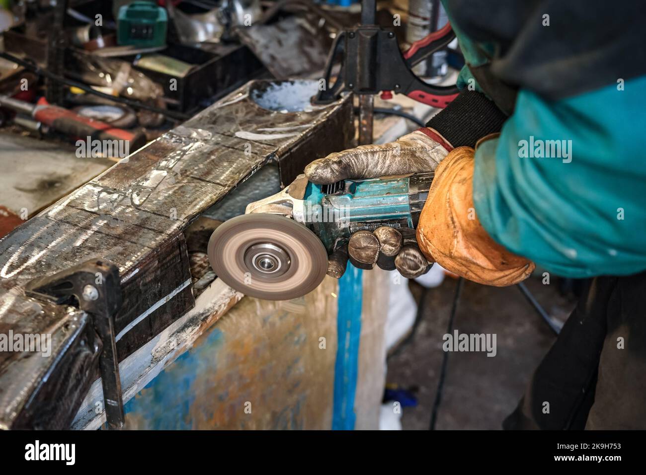 Man working with rotary angle grinder at workshop, closeup detail to ...